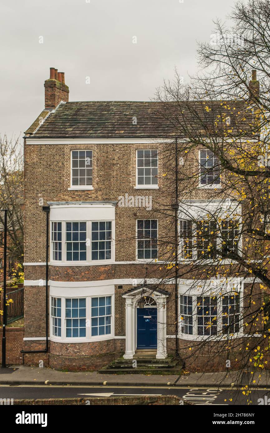 Facade of old traditional British brick townhouse behind a tree in York ...
