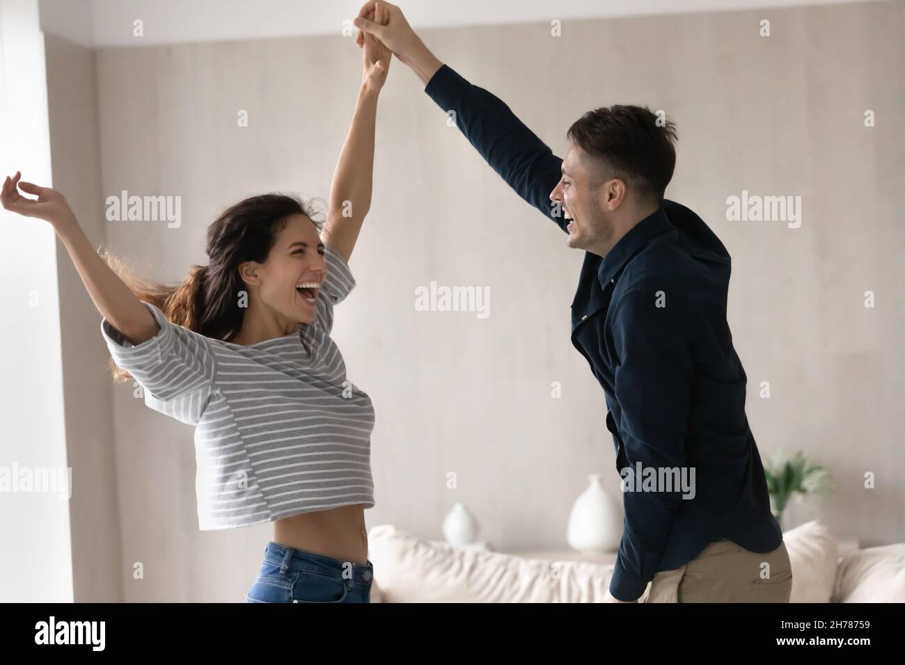 Cheery couple holding hands dancing at home Stock Photo - Alamy