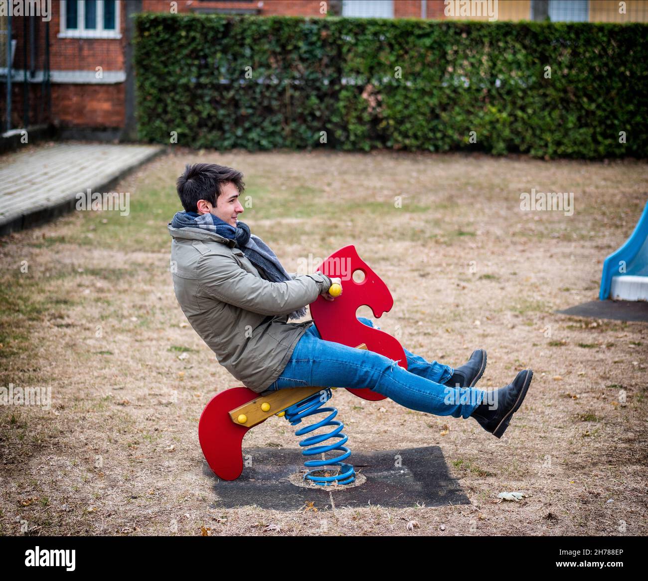 Young man reliving his childhood playing in playground Stock Photo - Alamy