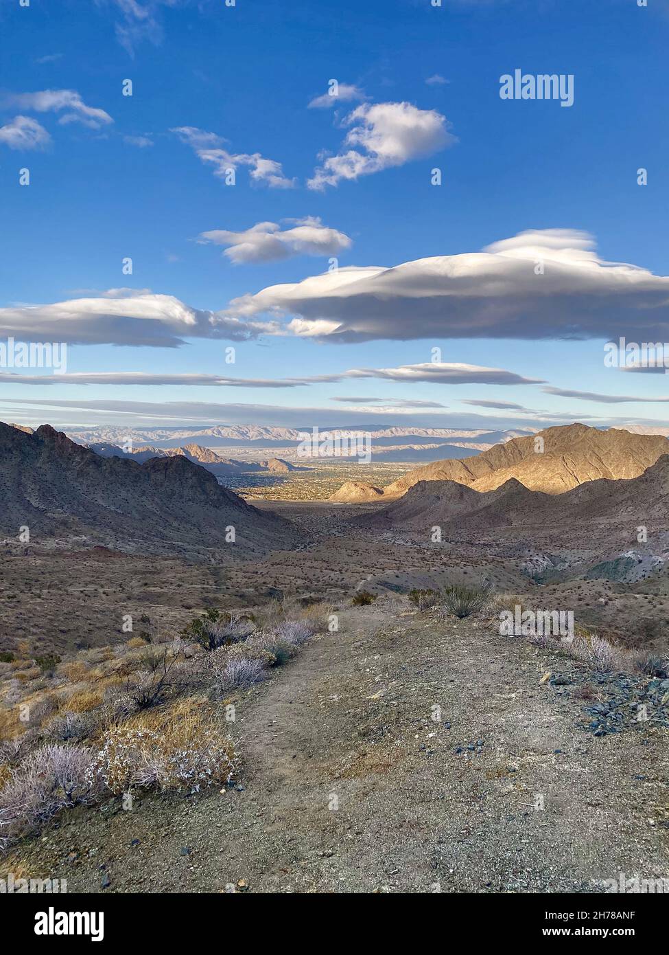A vertical shot of a dry field and rocky hills under a blue sky with ...