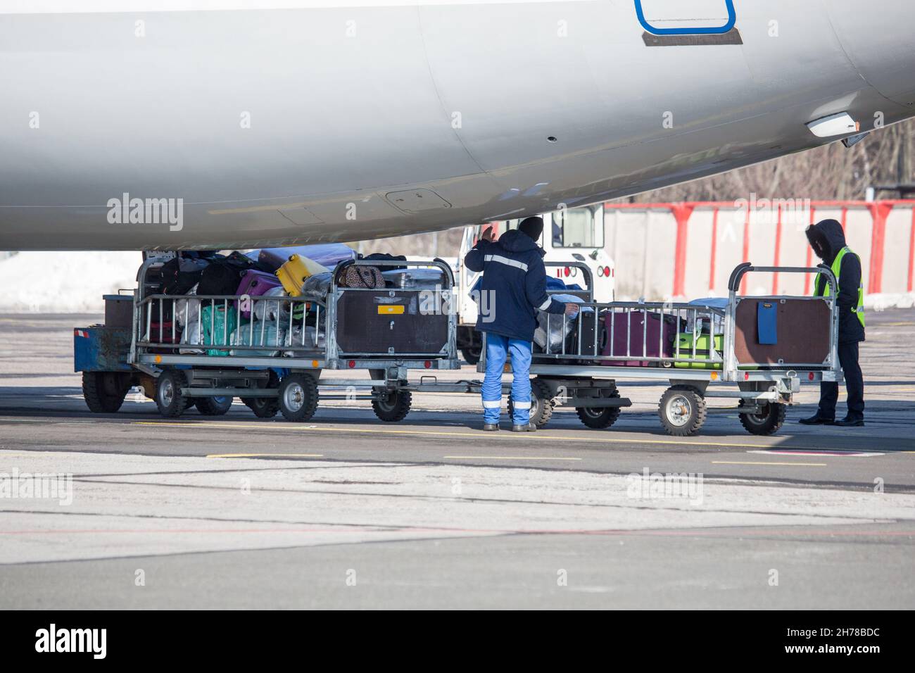 baggage loading at airport in winter. Luggage in carts near aircraft in ...