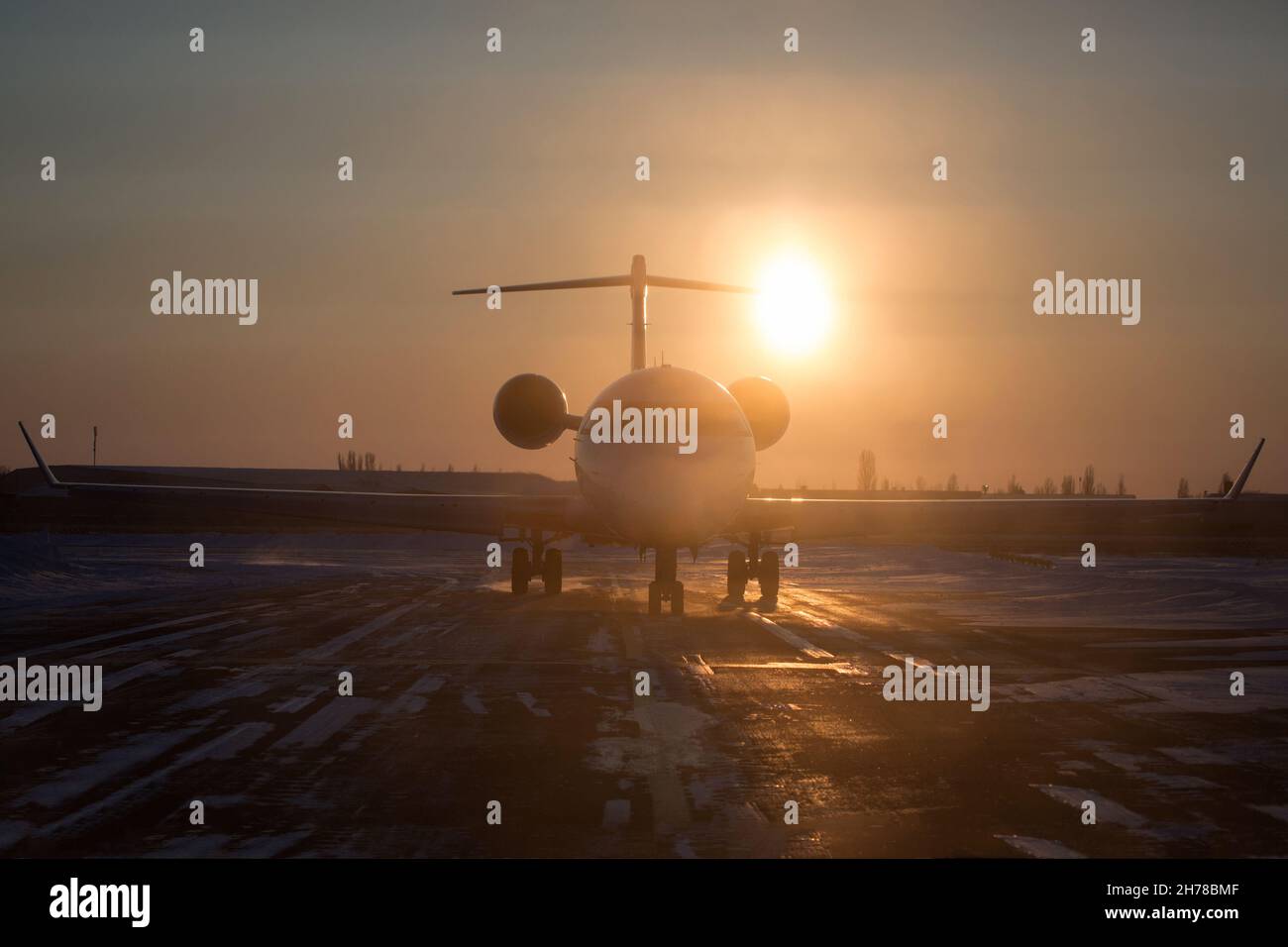 Plane in back rays of sunset. Passenger aircraft on runway in rays of ...