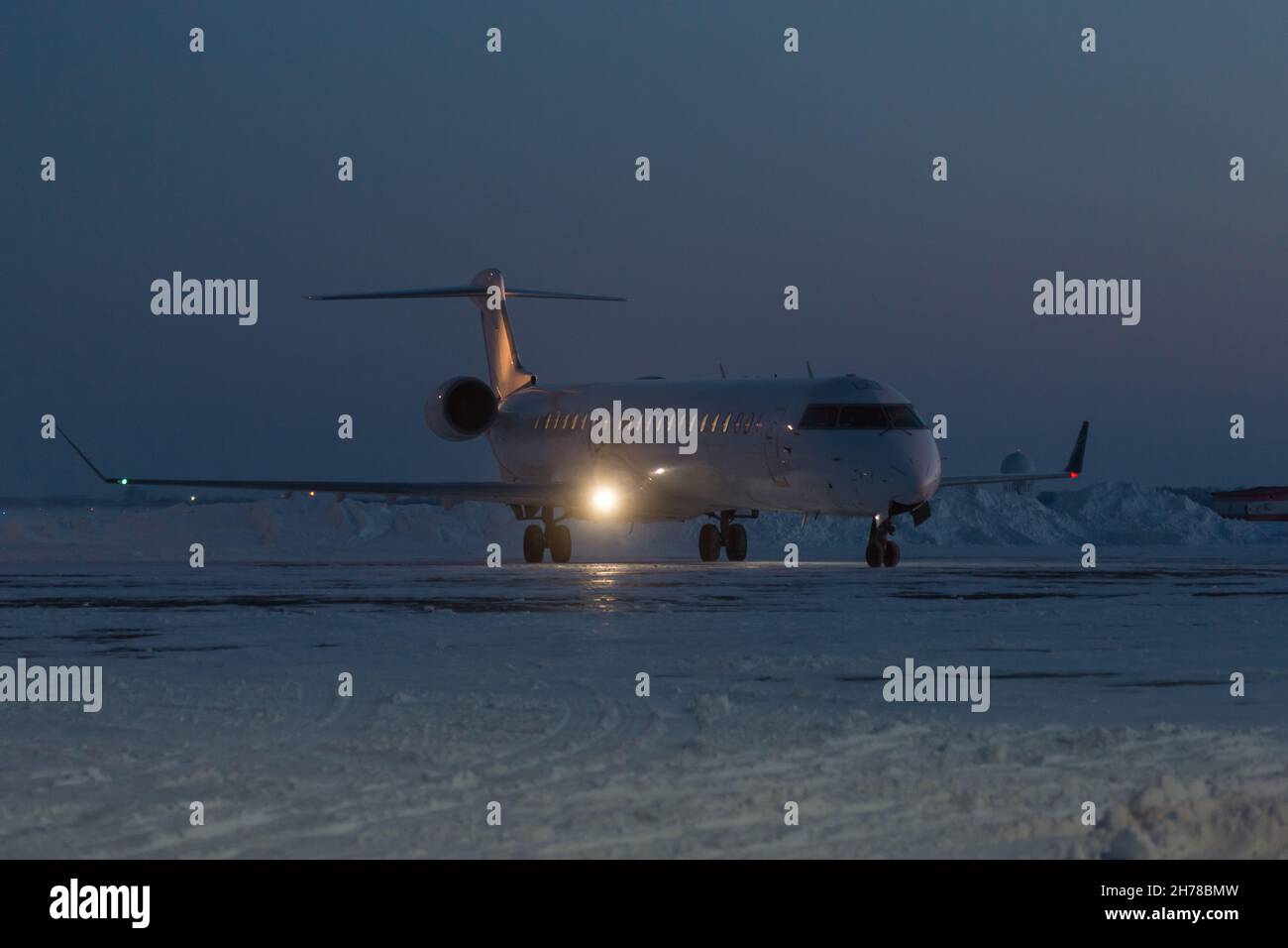 Passenger plane at airport in evening in winter. Airplane at a snowy ...