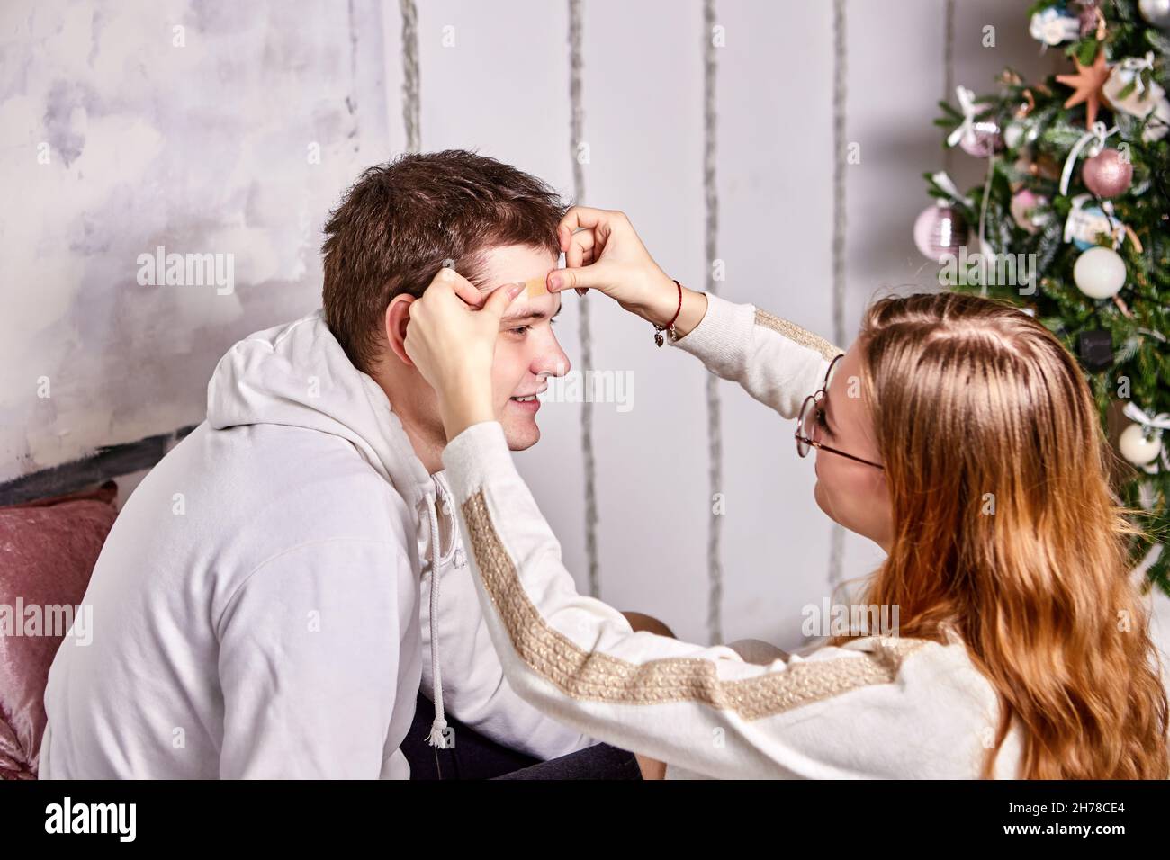 Woman applies medical plaster to wound on forehead of her husband, who ...