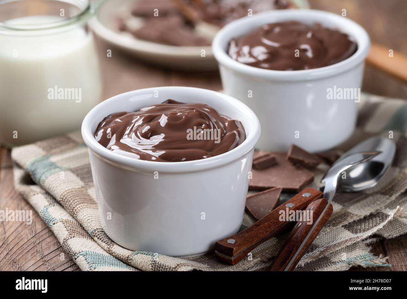 Closeup of creamy chocolate pudding in a white cup on a cloth napkin ...