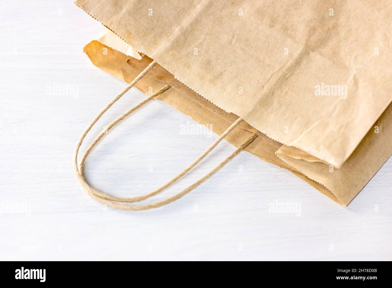 Beige craft paper bag on light wooden table with copy space. Eco ...