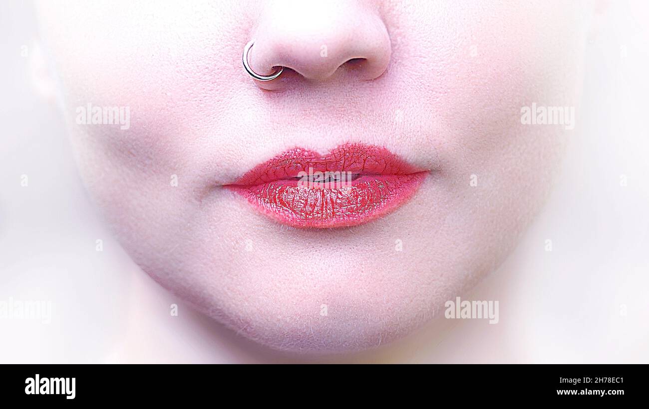 A female face with a piercing on her nose and pinky lipstick on her ...