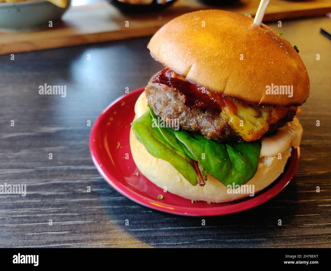 A closeup of a delicious slider hamburger on a red plate, on a wooden ...
