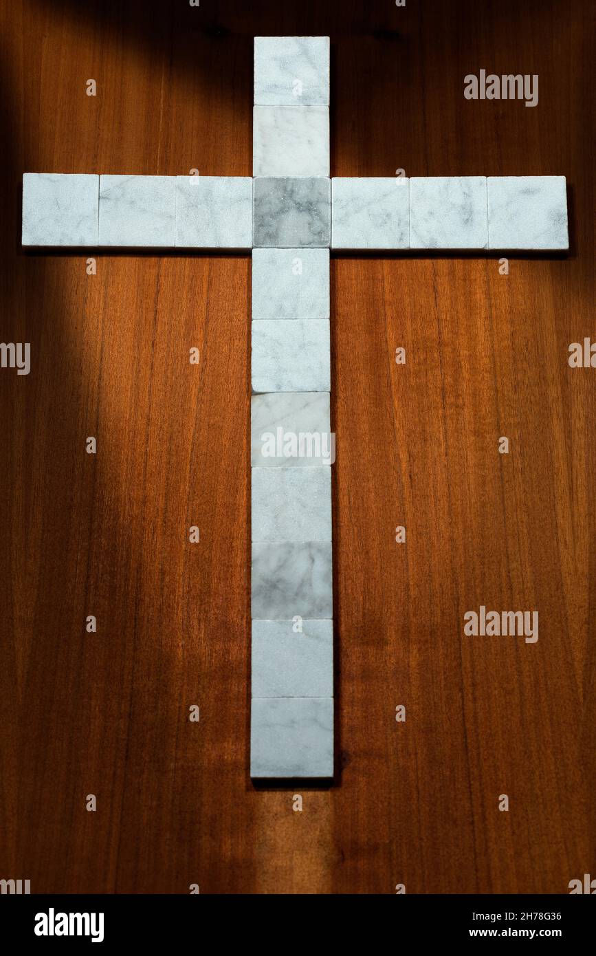 White marble cross on a wooden brown background with dark shadows Stock ...