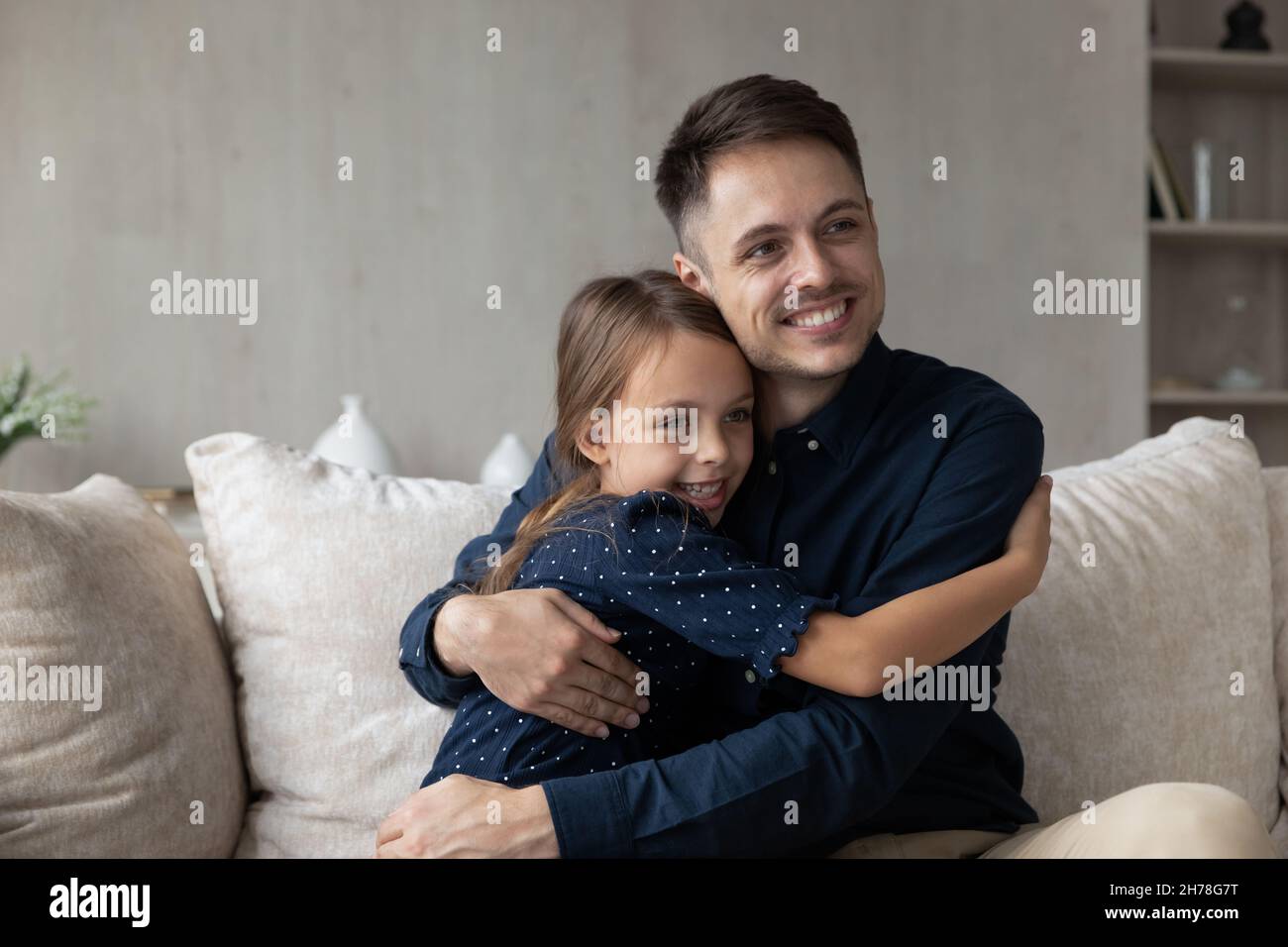 Loving dad cuddling little 6s daughter seated on sofa Stock Photo - Alamy