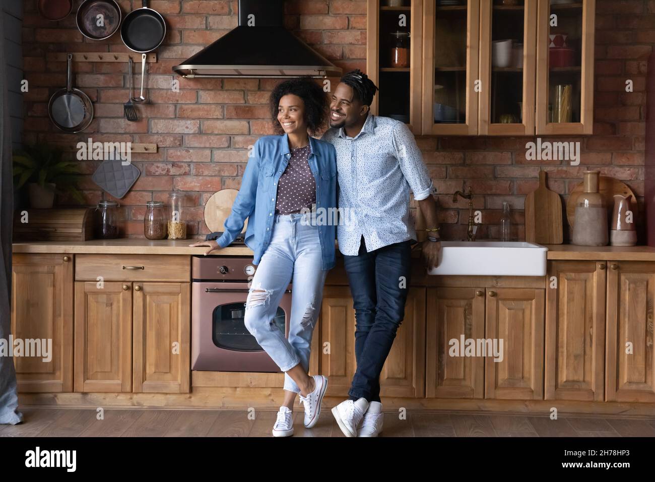 Happy dreamy young African American family couple looking in distance ...