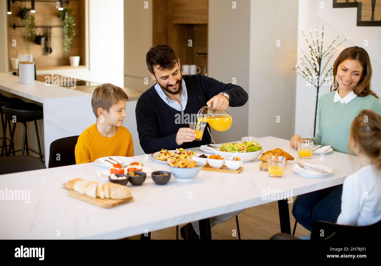 Young happy family talking while having breakfast at dining table at ...