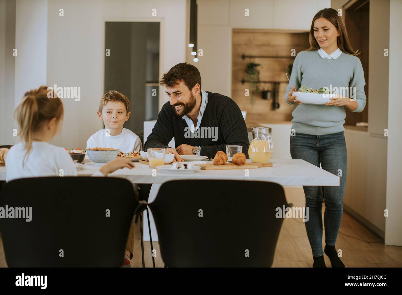 Young mother preparing breakfast for her family in the modern kitchen ...