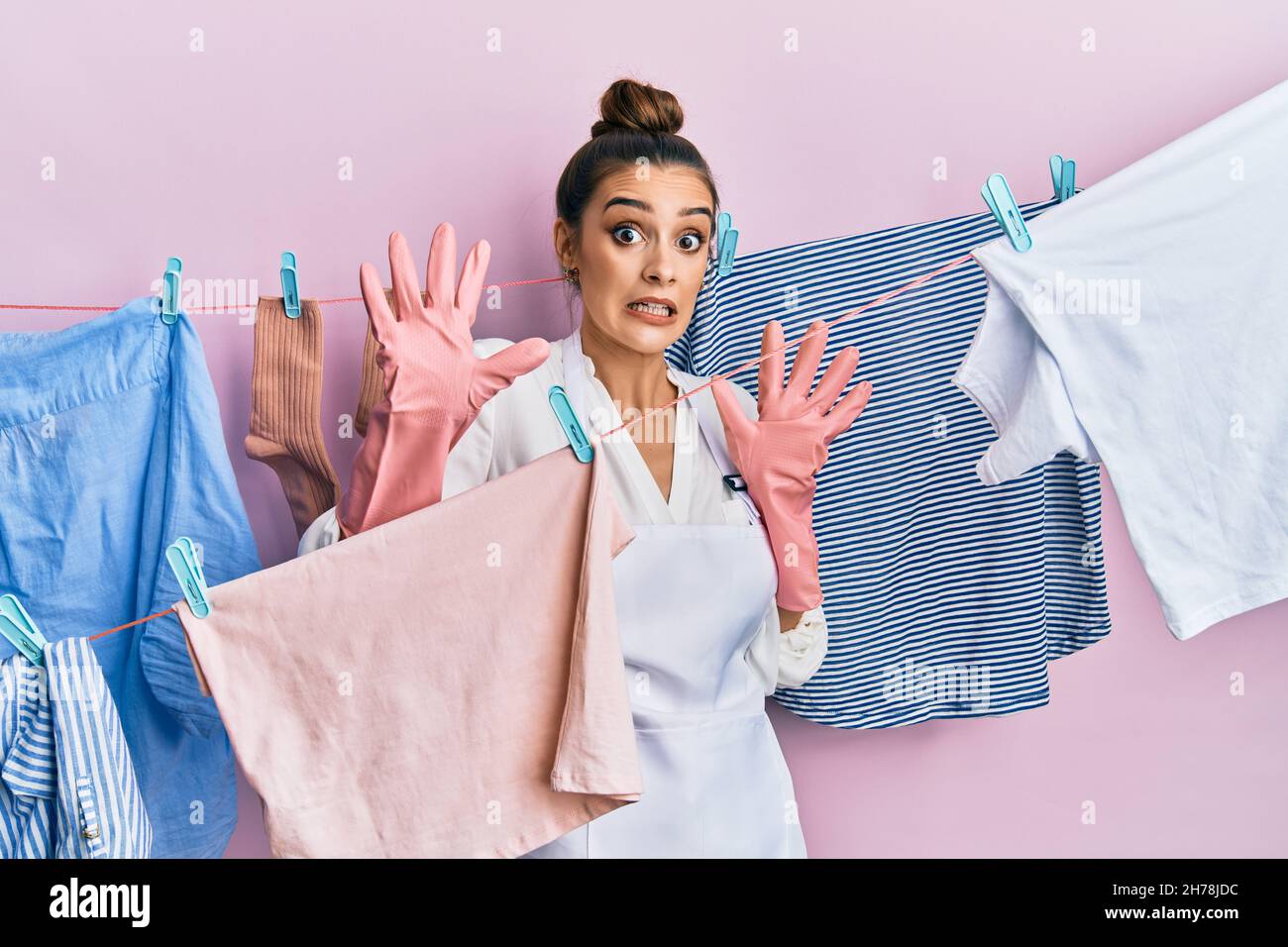 Beautiful brunette young woman washing clothes at clothesline afraid ...