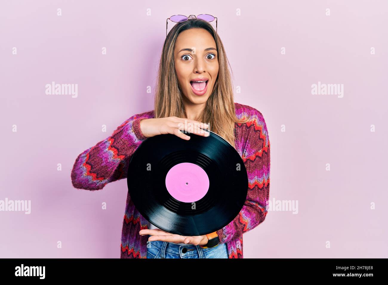 Beautiful hispanic woman wearing hippie style holding vinyl disc ...