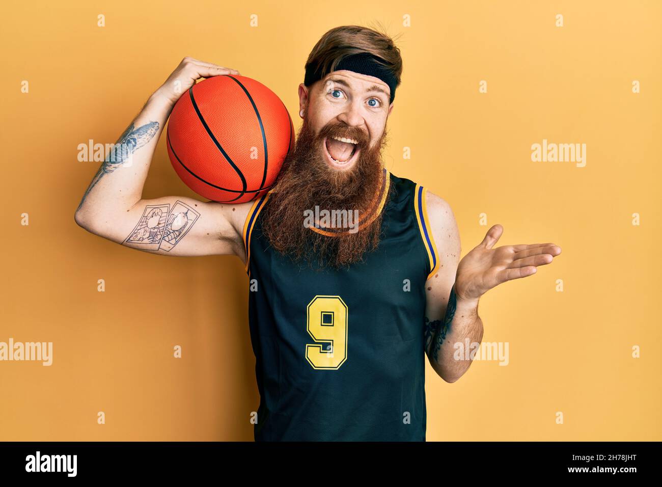 Redhead man with long beard wearing basketball uniform holding ball ...