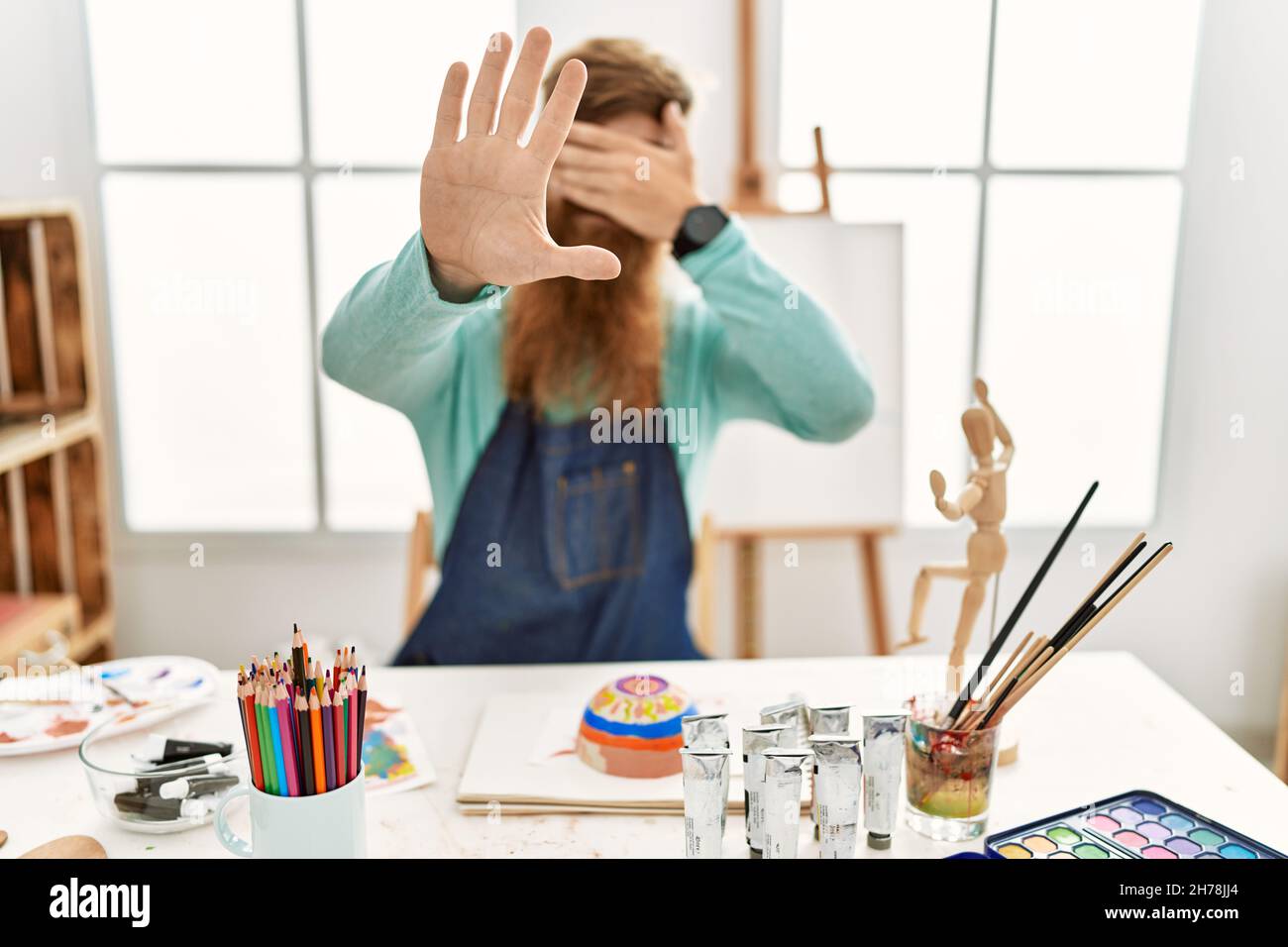 Redhead man with long beard painting clay bowl at art studio covering ...