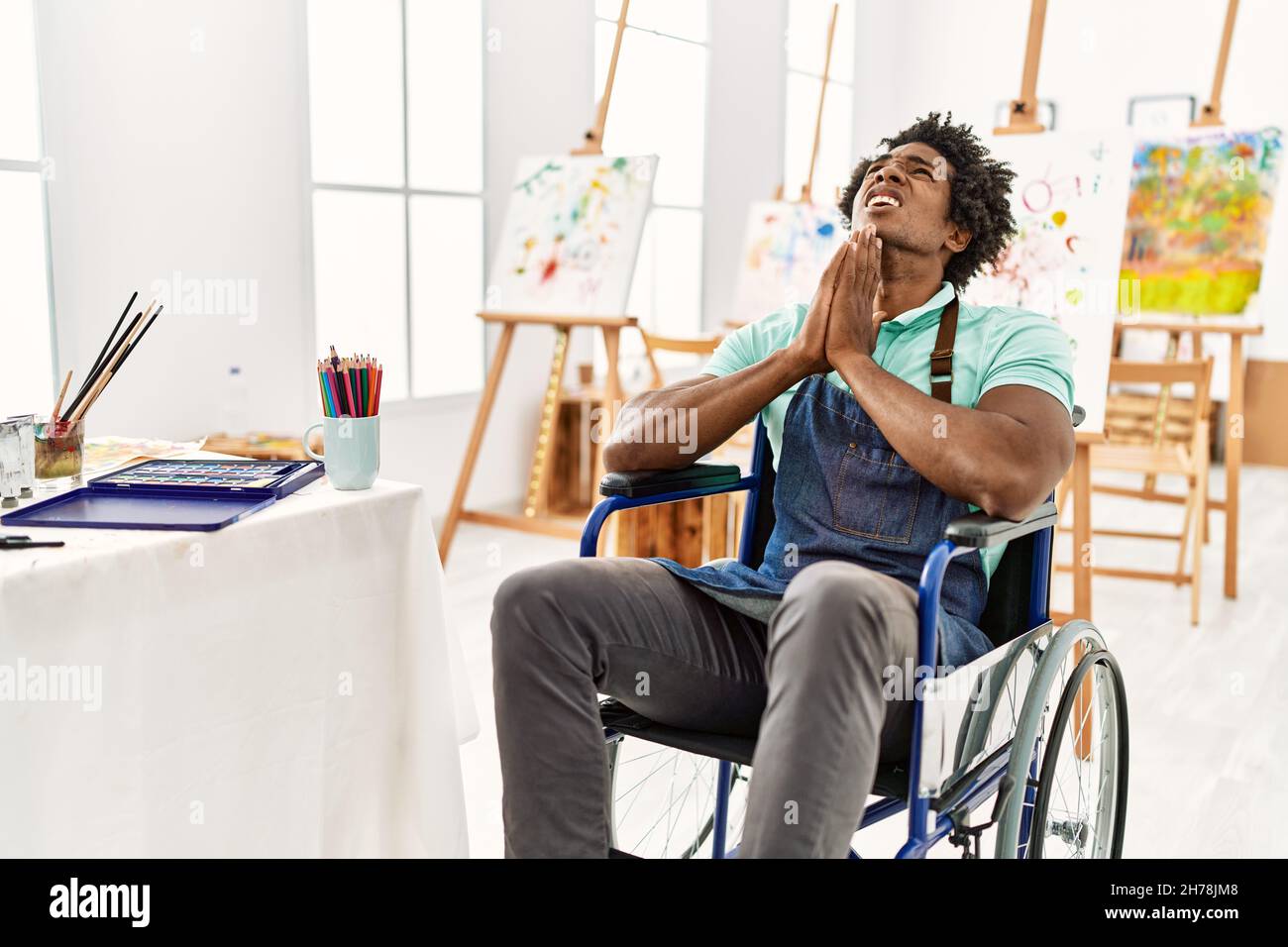 Young african american artist man sitting on wheelchair at art studio ...