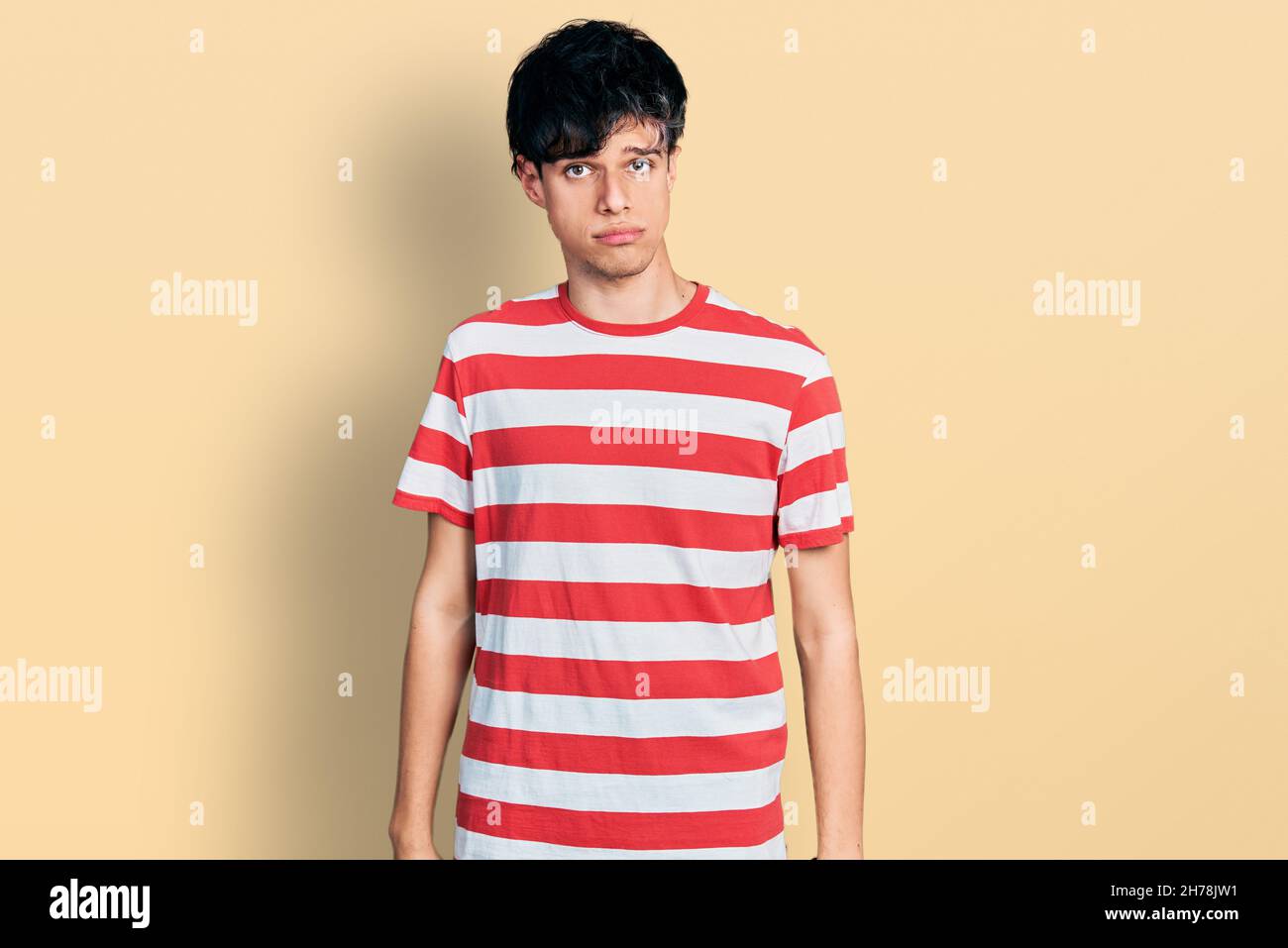 Handsome hipster young man wearing casual striped t shirt depressed and ...