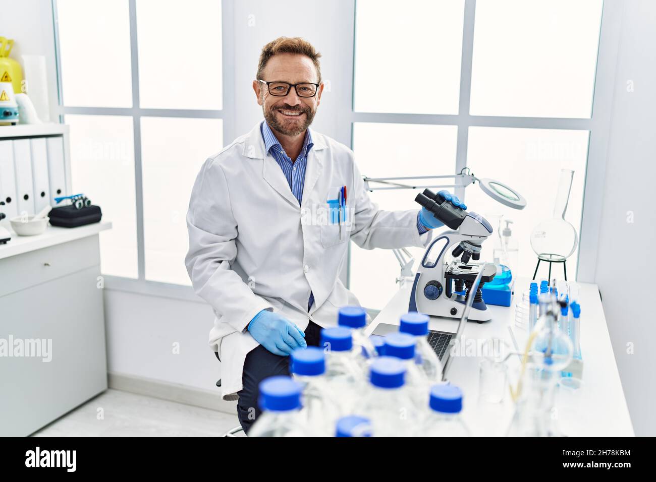 Middle age man working at scientist laboratory looking positive and ...