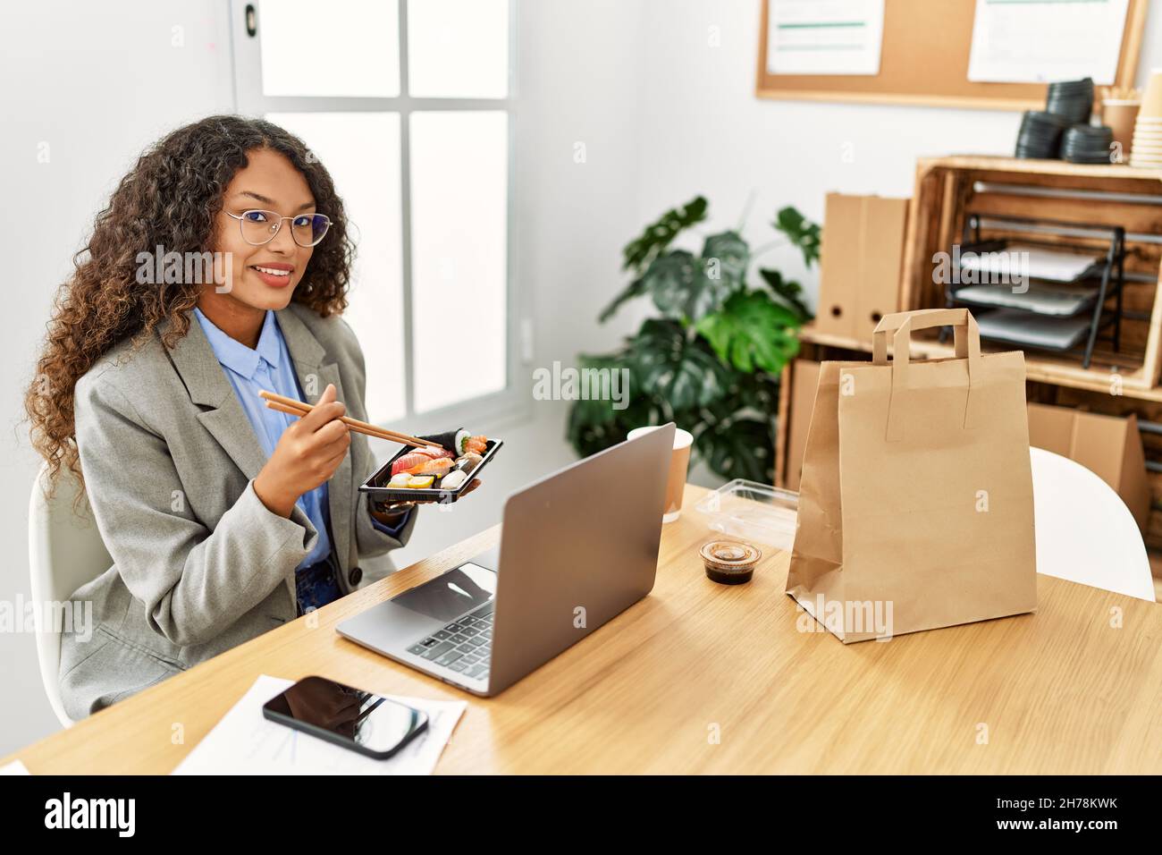 Young latin woman smiling confident eating sushi at office Stock Photo ...