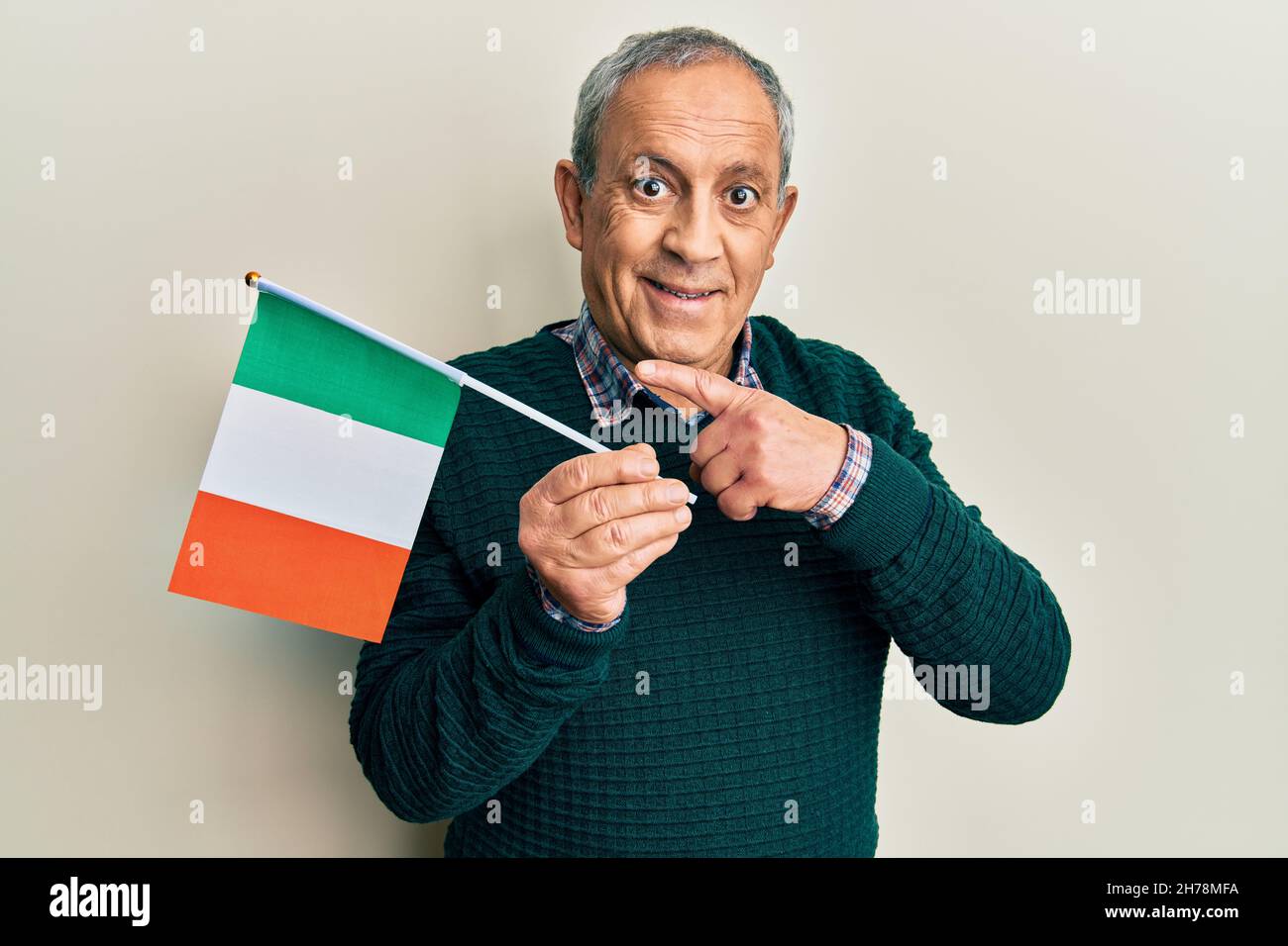 Handsome senior man with grey hair holding ireland flag smiling happy ...