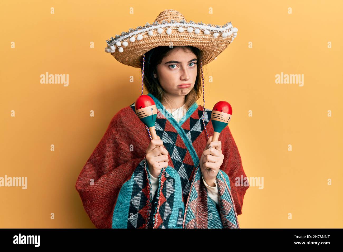 Young caucasian woman holding mexican hat using maracas depressed and ...