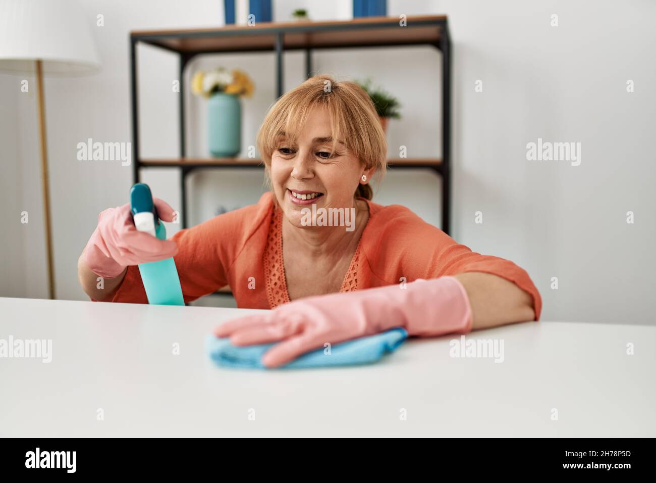 Middle age woman smiling happy cleaning using diffuser and rag at home ...