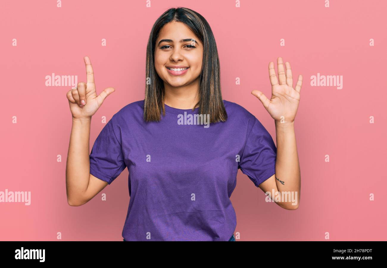 Young hispanic girl wearing casual purple t shirt showing and pointing ...