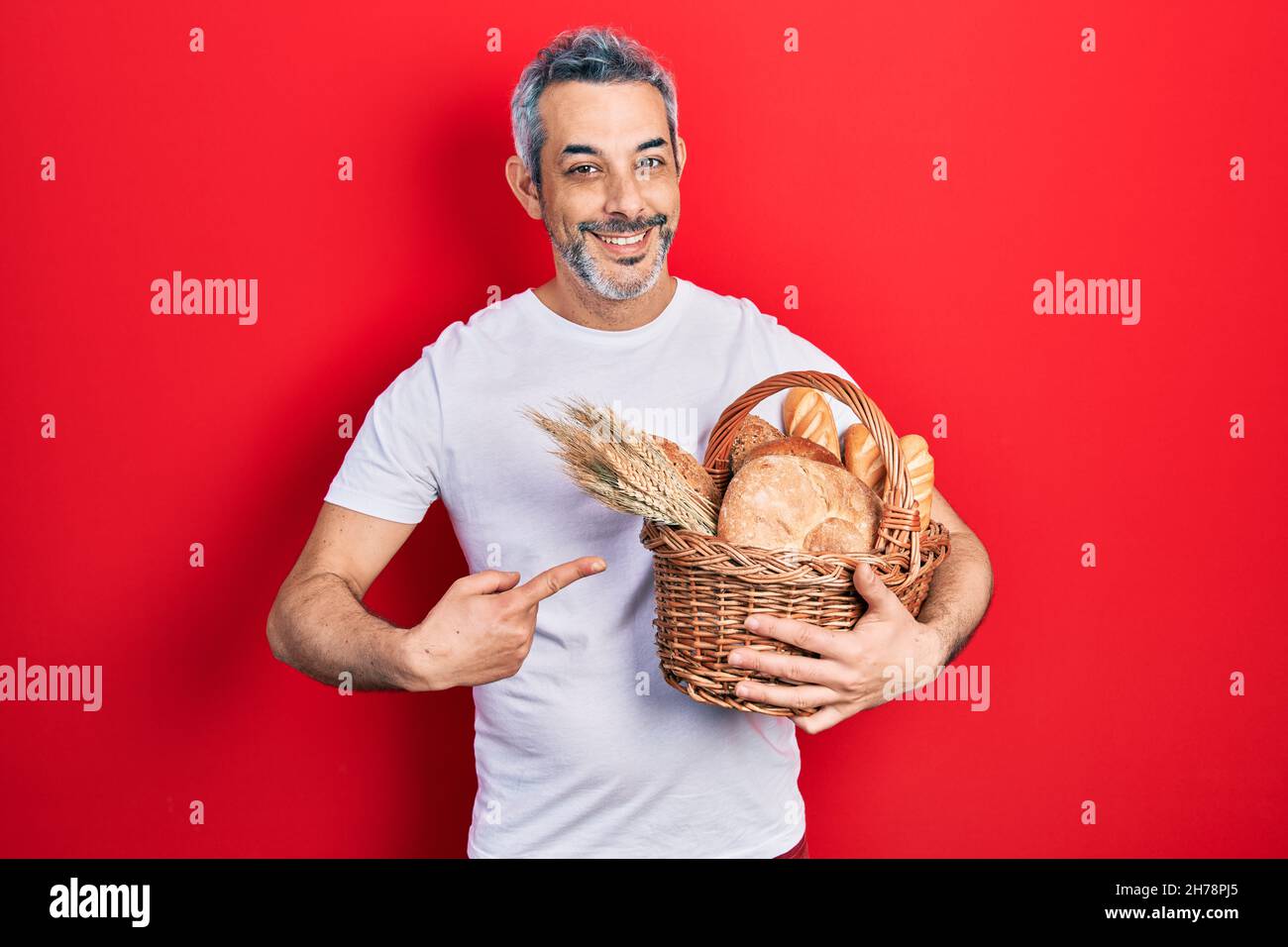 Handsome middle age man with grey hair holding wicker basket with bread ...