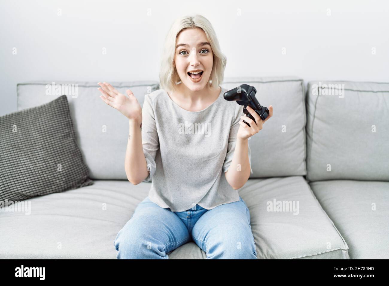 Young caucasian woman at home playing video game holding controller ...