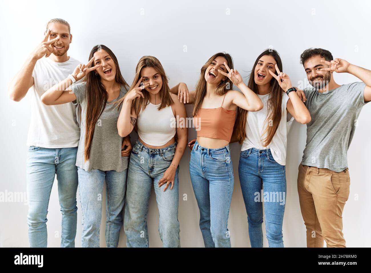 Group of young friends standing together over isolated background doing ...