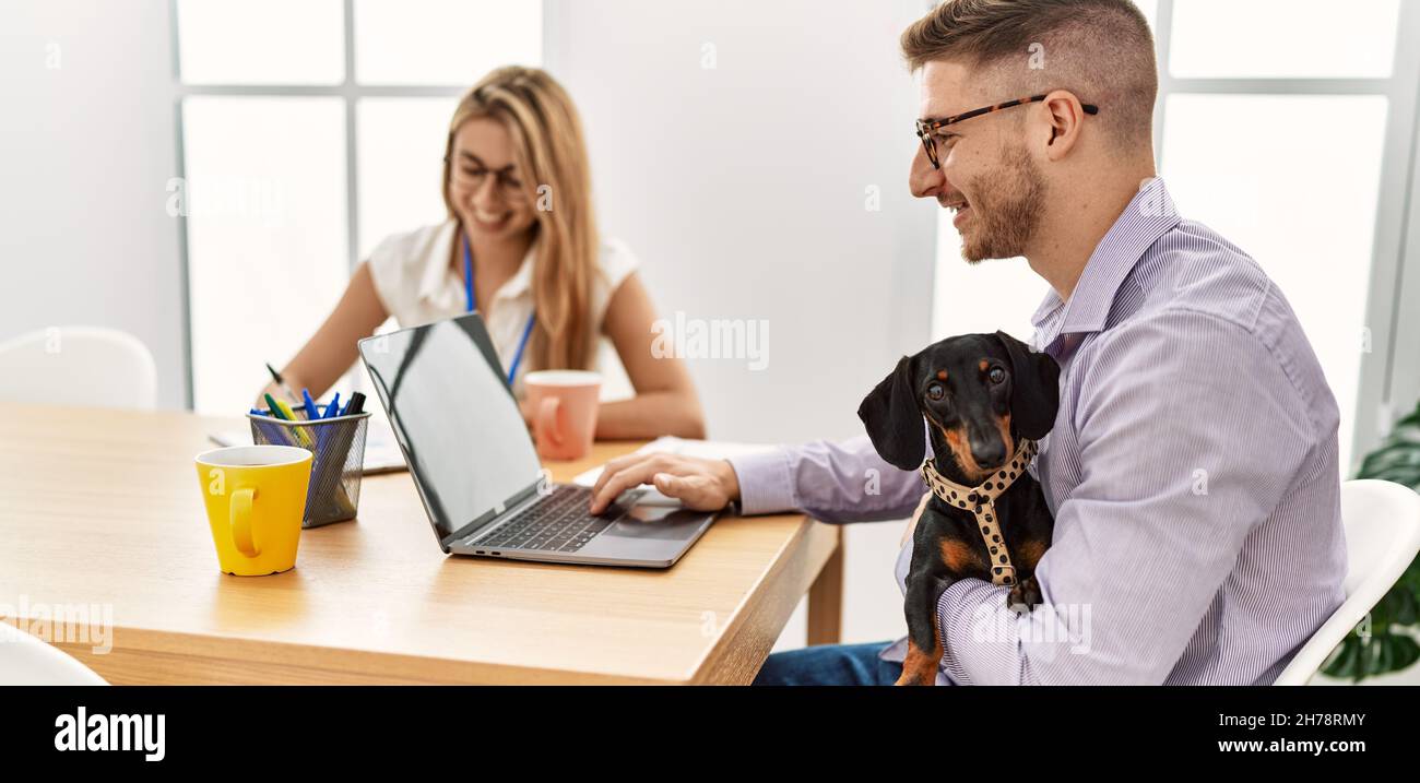 Two business workers smiling happy working with dog at the office Stock ...