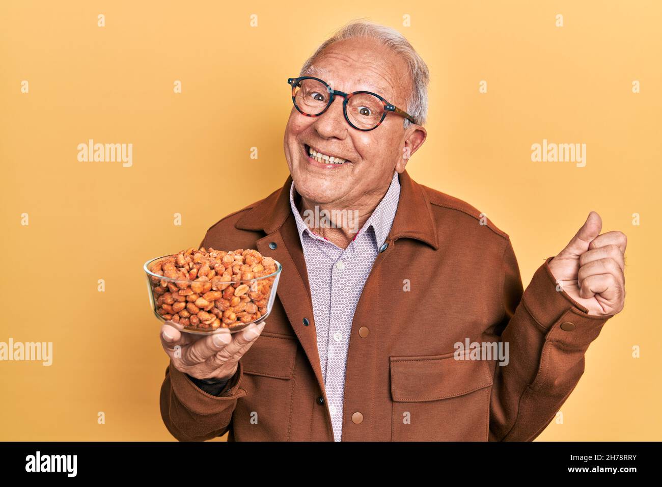Senior man with grey hair holding fried peanuts screaming proud ...