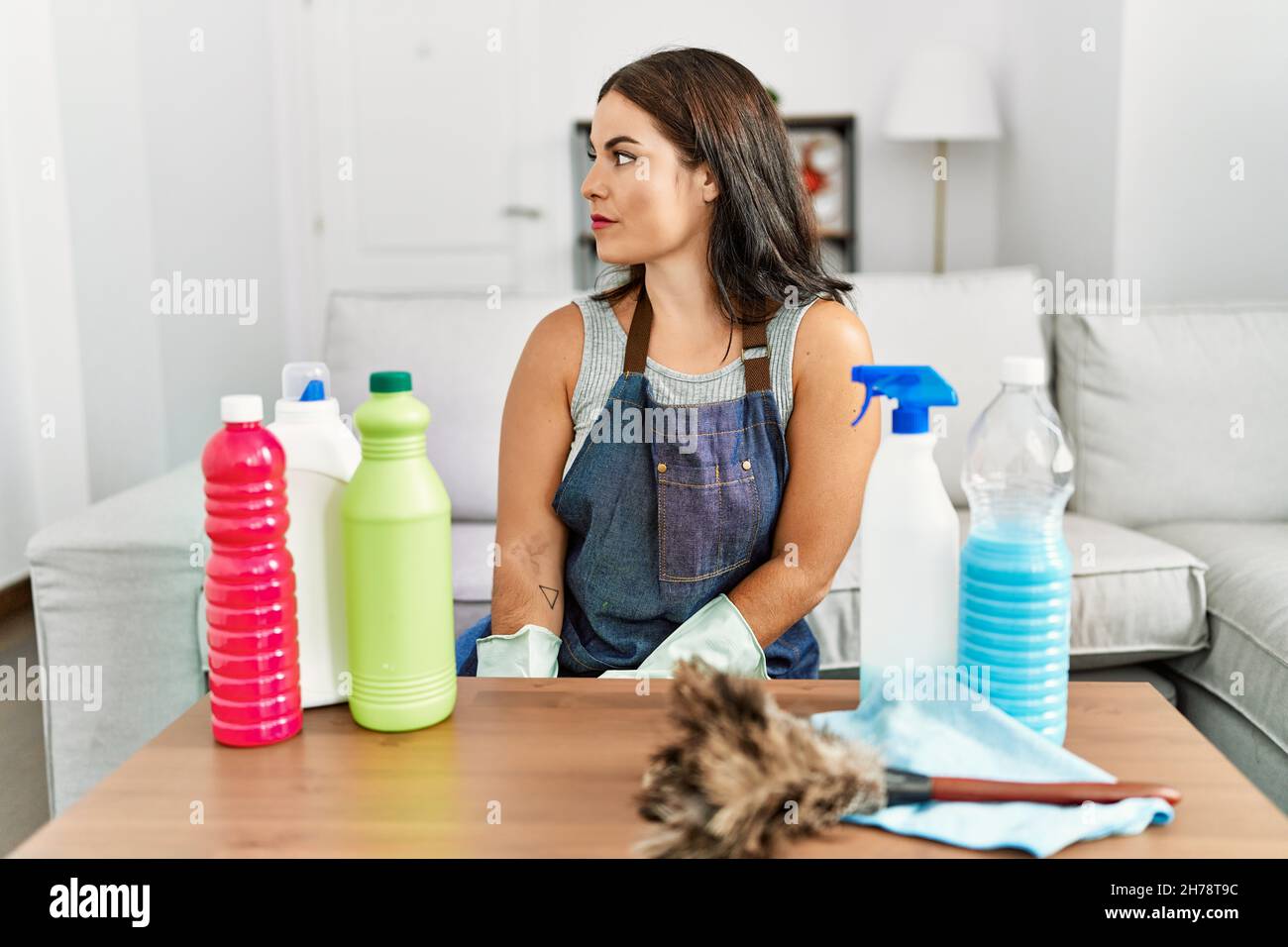 Young brunette woman wearing cleaner apron and gloves cleaning at home ...