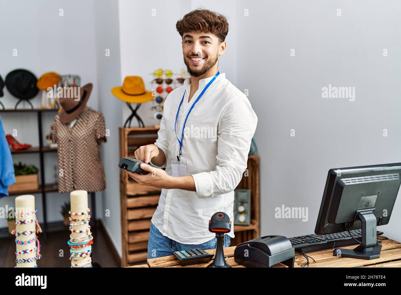 Young arab man smiling confident using data phone device at clothing ...