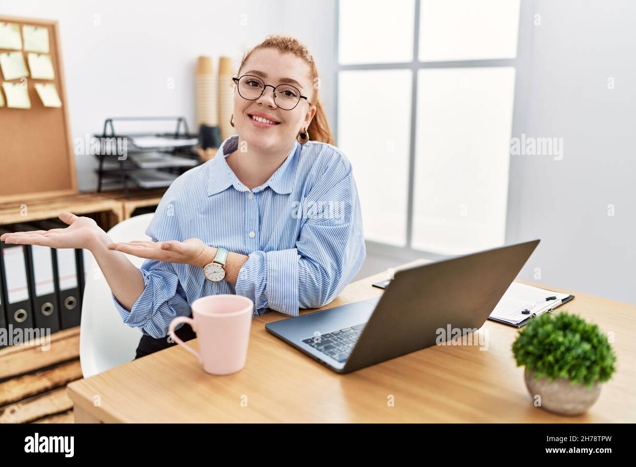 Young redhead woman working at the office using computer laptop ...