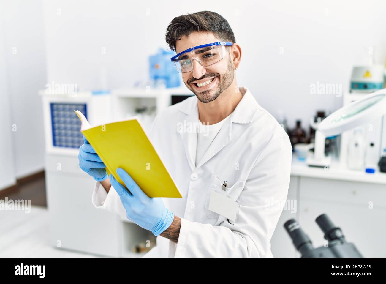 Handsome hispanic man working as scientific reading a book at ...