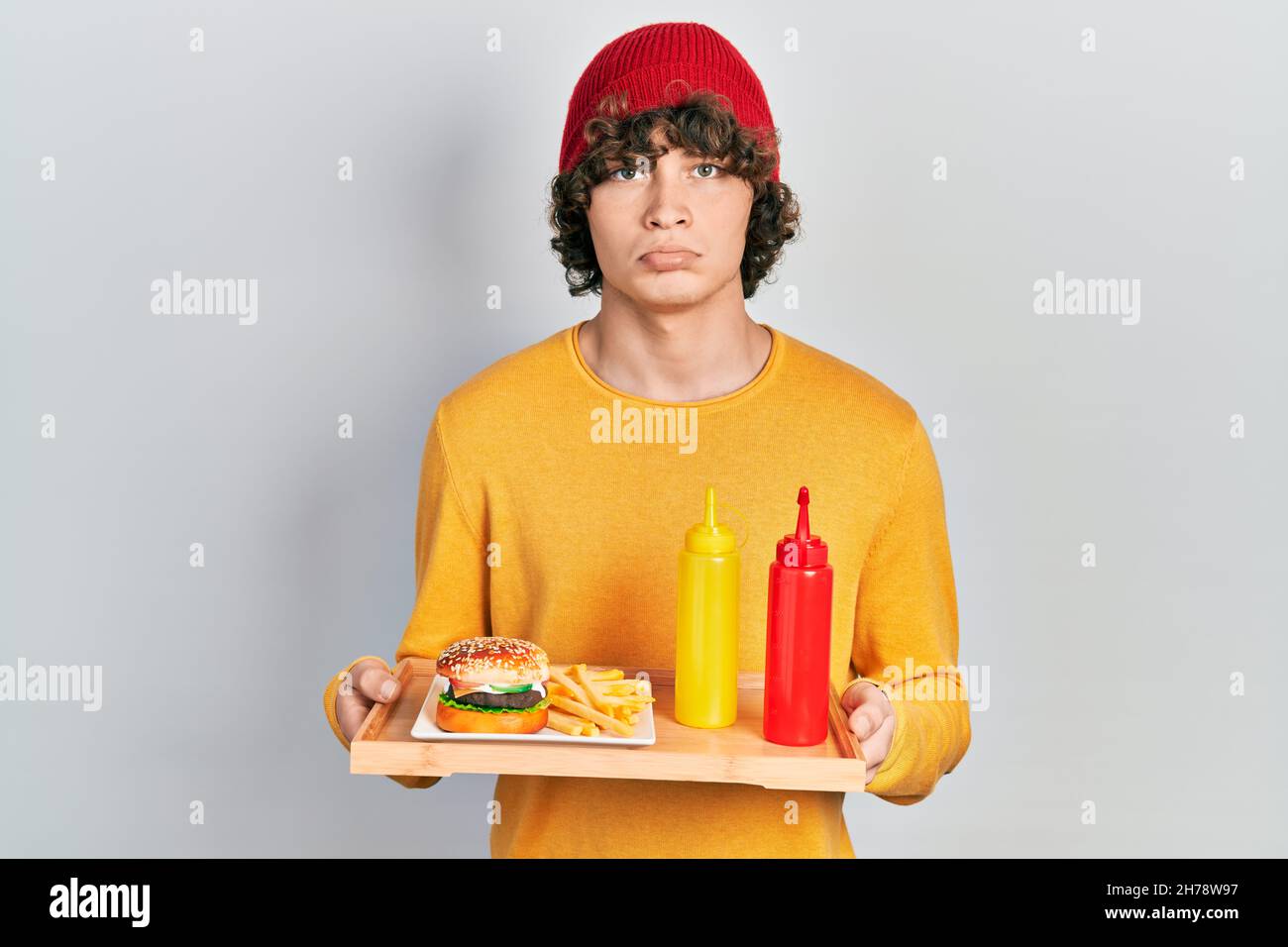 Handsome young man eating a tasty classic burger with ketchup and ...