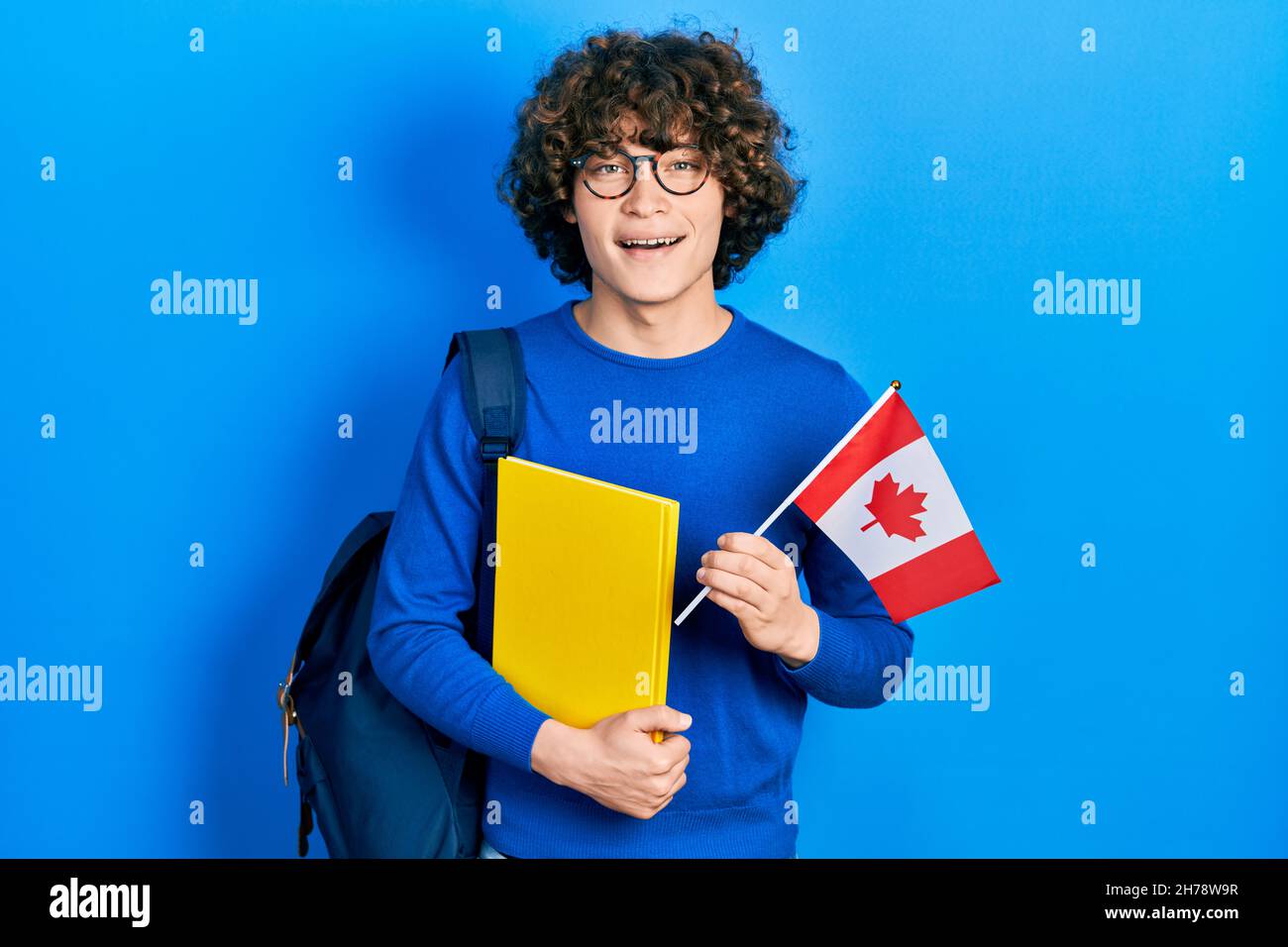 Handsome young man exchange student holding canada flag smiling and ...