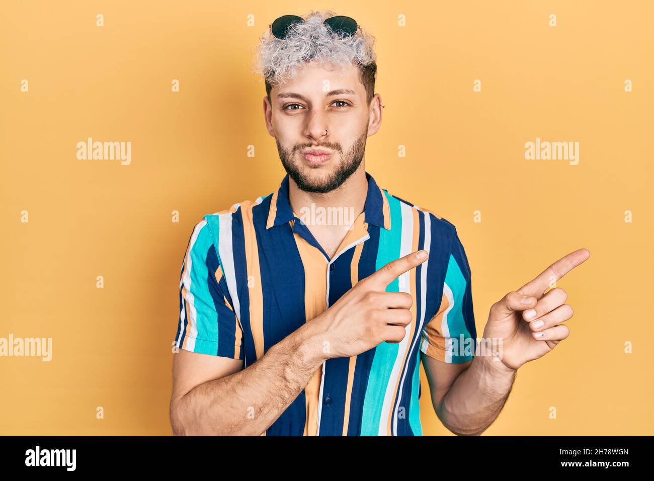 Young hispanic man with modern dyed hair pointing with fingers to the ...