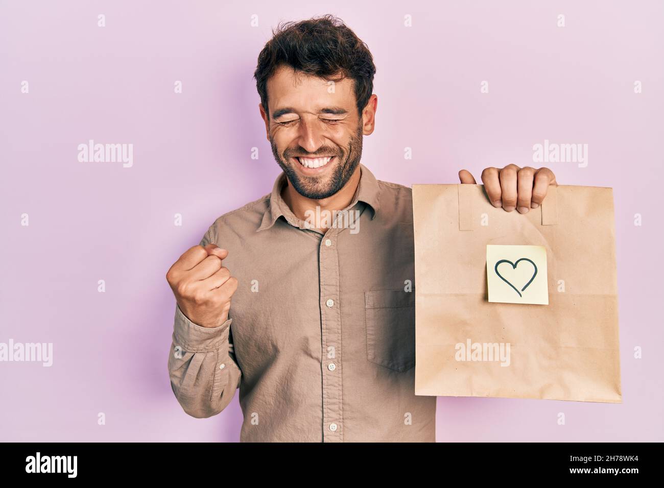 Handsome man with beard holding delivery paper bag with heart reminder ...