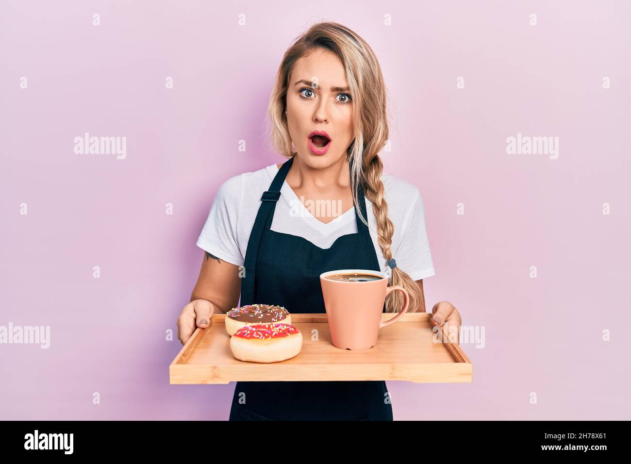 Beautiful young blonde woman wearing waitress apron holding breakfast ...