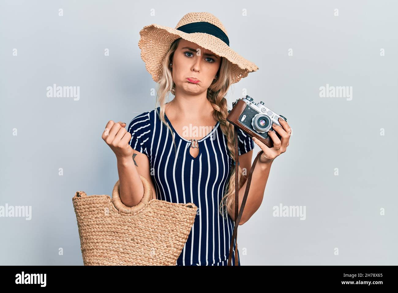 Beautiful young blonde woman holding vintage camera depressed and worry ...