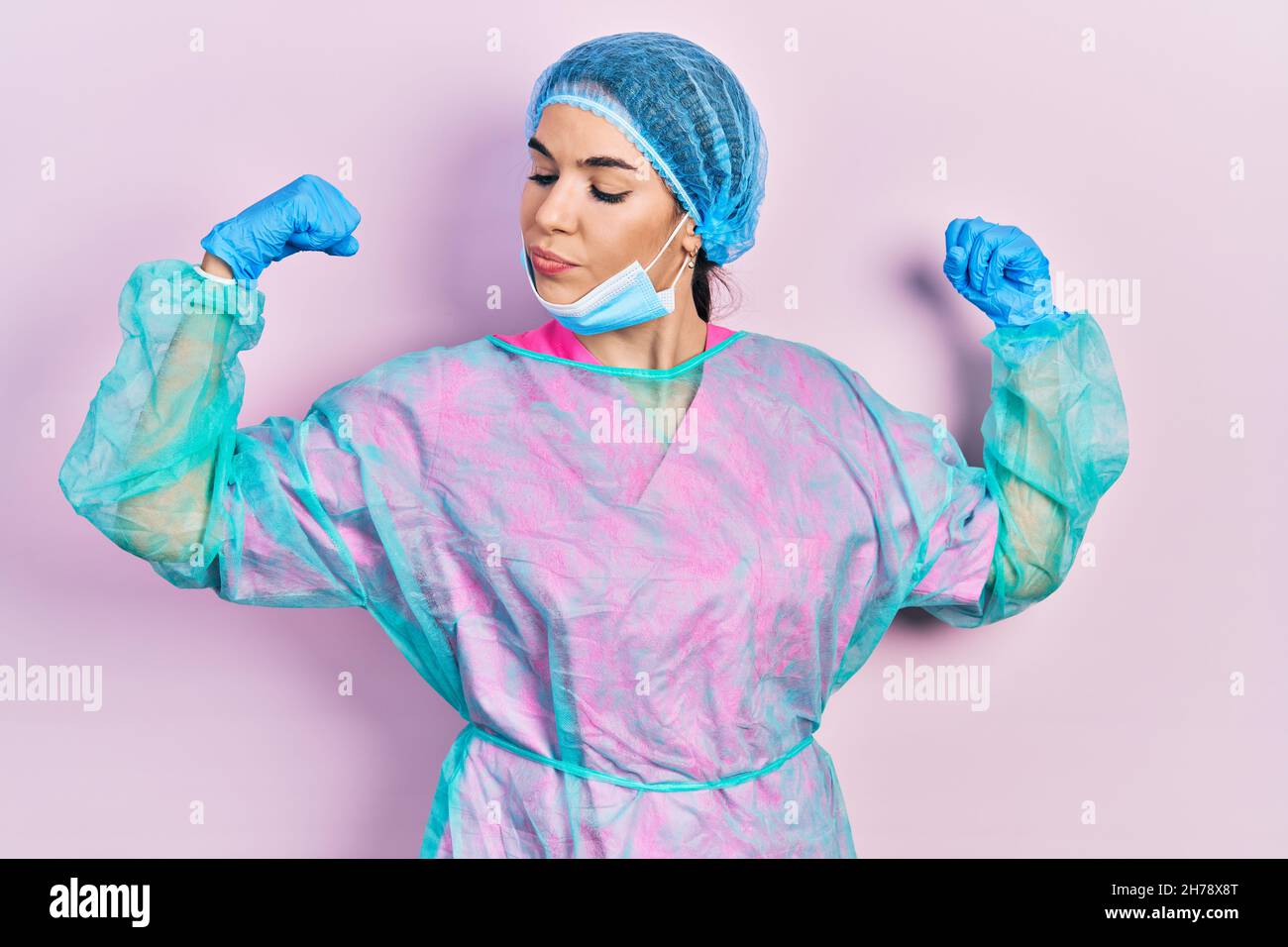 Young brunette woman wearing surgeon uniform and medical mask showing ...