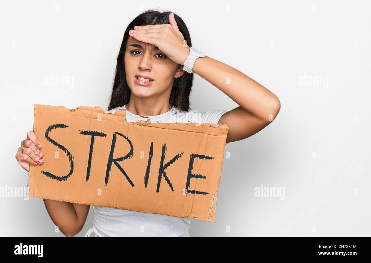 Young hispanic girl holding strike banner cardboard stressed and ...