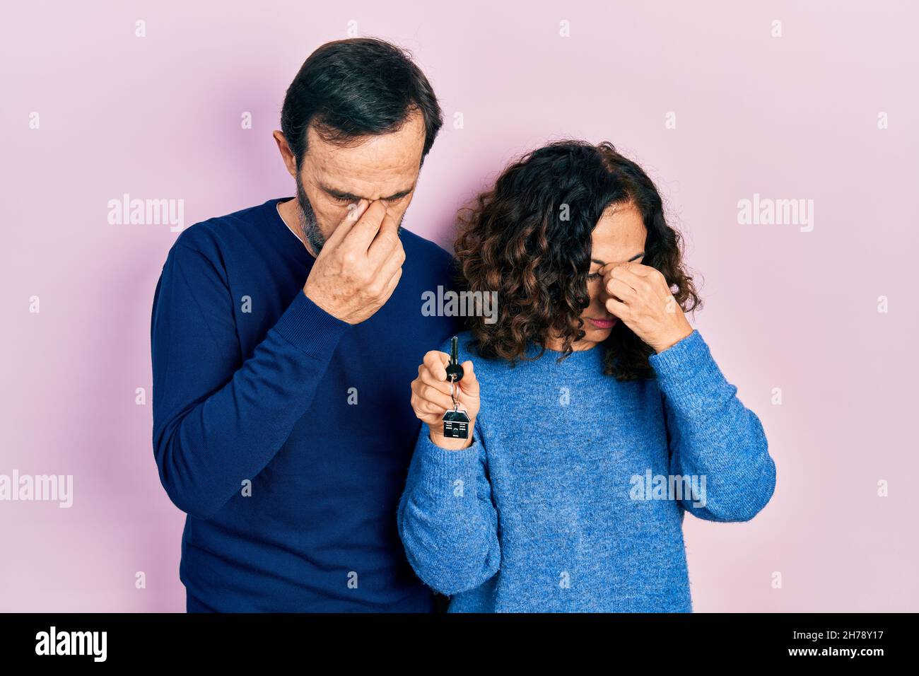 Middle age couple of hispanic woman and man holding keys of new home ...