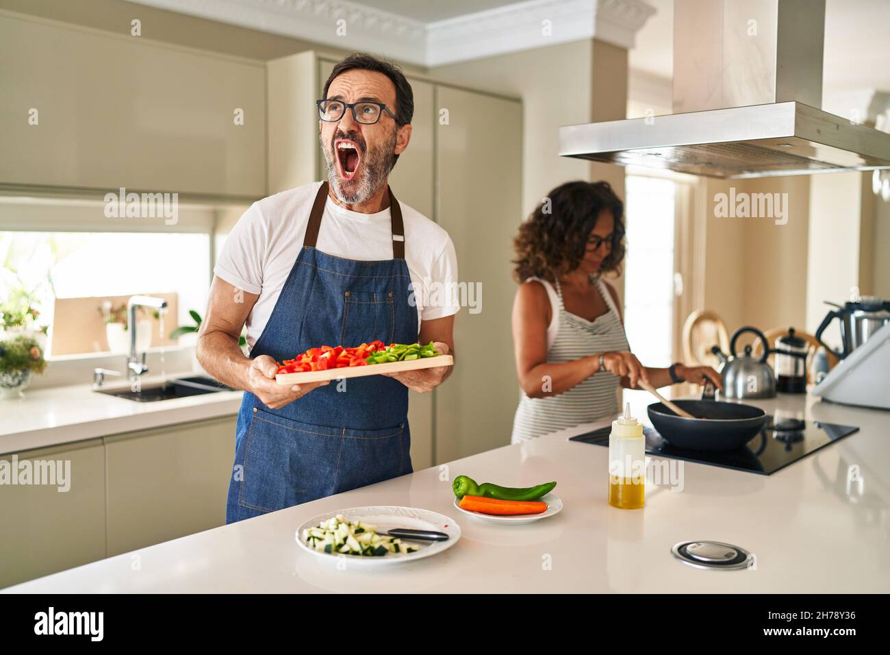 Middle age couple cooking mediterranean food at home angry and mad ...
