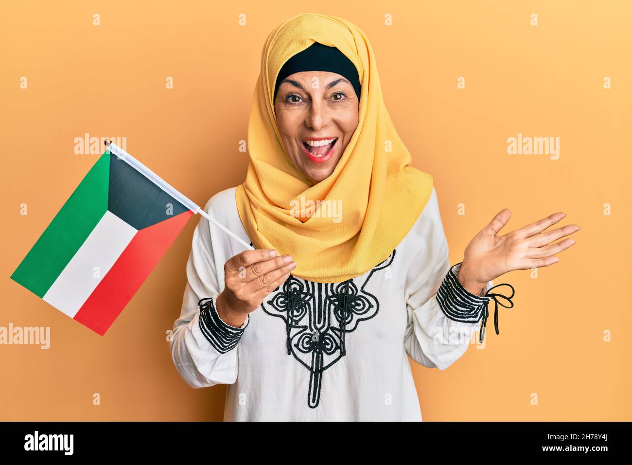 Middle age hispanic woman wearing hijab holding kuwait flag celebrating ...