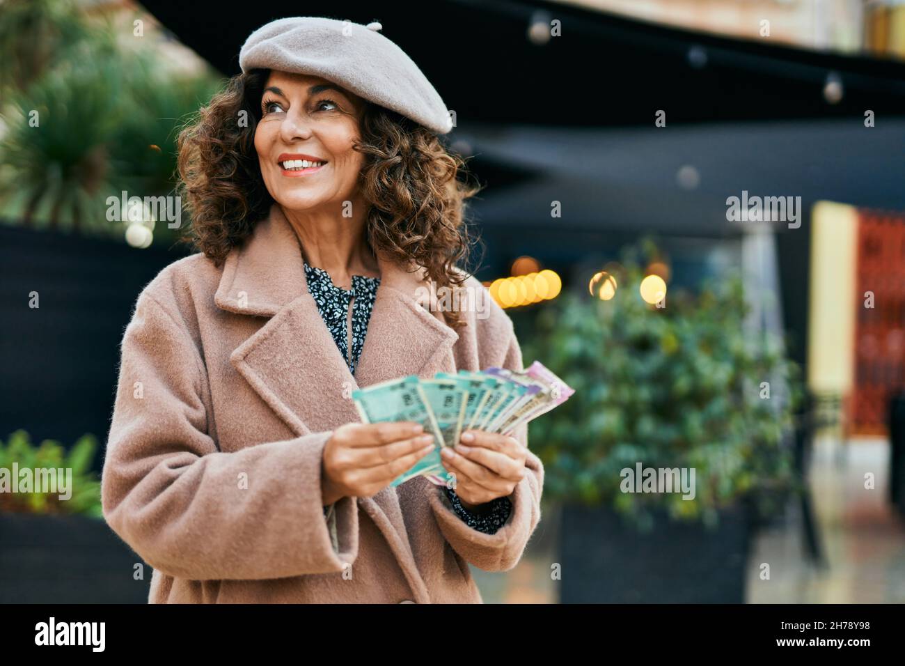 Middle age hispanic woman smiling happy counting indian rupee banknotes ...